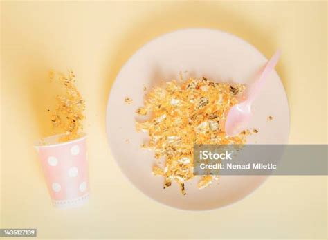 밝은 파스텔 노란색 배경에 흰색 점이 있는 분홍색 숟가락과 종이 유리가 있는 파스틸 분홍색 접시에 황금 식사 최소한의 창조적 인