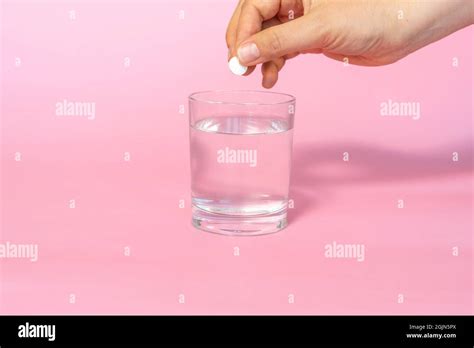 Womans Hand Throws A Pill Into A Glass Of Water Pink Background Stock