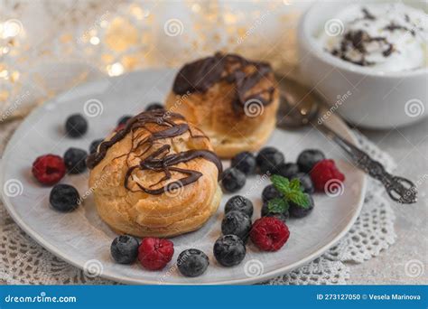 Homemade Eclairs With Vanilla Filling Fresh Berries And Cup Of Ice