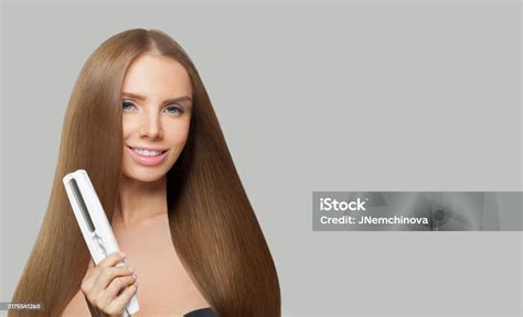 흰색 배경에 철을 곧게 펴는 긴 스트레이트 건강한 헤어 스타일을 가진 웃는 여자의 스튜디오 초상화 뷰티 헤어 케어 헤어 트리트먼트 및 화장품 컨셉 25 29세에 대한 스톡