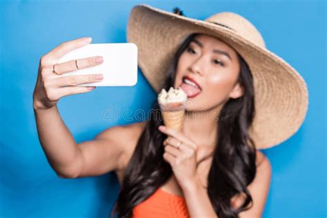 Beautiful Asian Woman In Swimsuit And Beach Hat Licking An Ice Cream