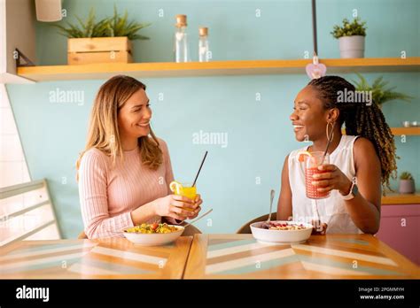 Two Pretty Young Black And Caucasian Woman Having Good Time Drinking