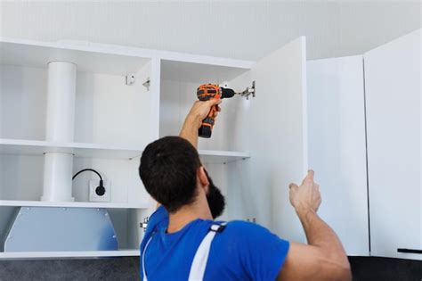 Premium Photo A Man In Uniform Screws The Kitchen Cabinet Doors With An Electric Screwdriver