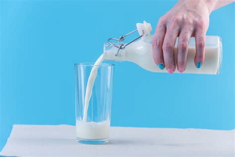 여자의 손을 파란색 배경에 유리로 유리 병에서 신선한 우유를 따른다 칼슘과 건강 한 낙농 제품 0명에 대한 스톡 사진 및 기타 이미지 Istock