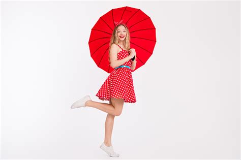 빨간 물방울 무늬 드레스를 입고 복고풍의 매력과 즐거운 우아함을 보여주는 흰색 배경에 우산을 쓴 쾌활한 여자 16 17 살에 대한 스톡 사진 및 기타 이미지 Istock