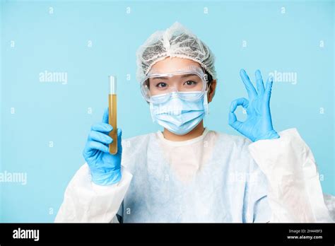Laboratory Worker Nurse In Personal Protective Equipment Showing Sample In Test Tube And Okay