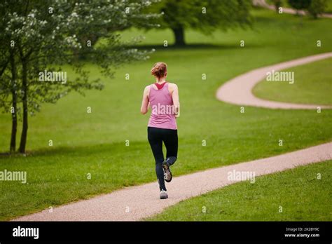 Just Her And The Path Rearview Shot Of A Woman Jogging Along A