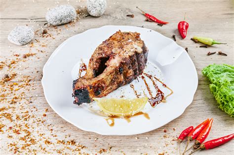 밝은 나무 테이블에 허브와 향신료와 흰 접시에 구운 생선 스테이크에서 보기를 닫습니다 메뉴 또는 조리법에 대 한 해산물 텍스트의 공간을 복사 합니다 0명에 대한 스톡 사진