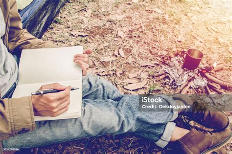 아시아 젊은 사람이 앉아 읽고 이며 텐트 밖에 서 책을 쓰기 혼자 숲에서 캠핑 T 셔츠에 대한 스톡 사진 및 기타 이미지 T