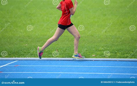 Atleta De Sexo Femenino Joven Que Corre En El Gblu De La Pista Del Atletismo Del Color Foto De