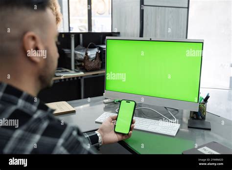 Businessman Working At A Modern Office Desk Using A Computer And Smartphone With A Green Screen