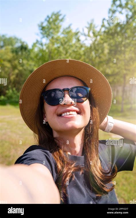 Young Woman With Sunglasses And Straw Hat Laughing And Taking A Selfie