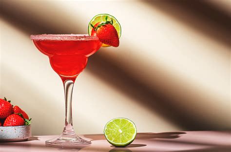 딸기 마가리타 은색 데킬라 라임 주스 리큐어 딸기 및 설탕 테두리가있는 유리에 얼음이 들어간 여름 알코올 칵테일 음료 베이지색 분홍색 바닐라 배경입니다 딸기에 대한 스톡