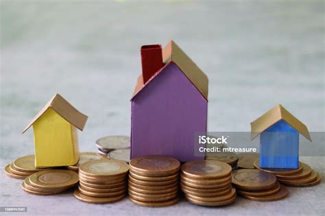 쌓인 동전 더미에 다색 골판지 집의 클로즈업 이미지 전경 얼룩덜룩 한 회색 배경 가족 재정 부동산 및 휴가 저축 개념에 중점을
