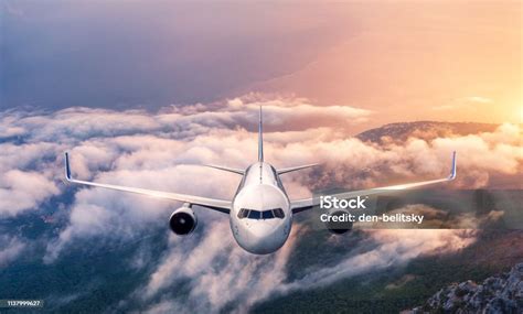 夏天日落時 飛機在雲層上空飛行風景與客機 低雲 大海 黃昏紫色的天空飛機的正面視圖商務旅行商用飛機鳥瞰 照片檔及更多 商用客機 照片 Istock
