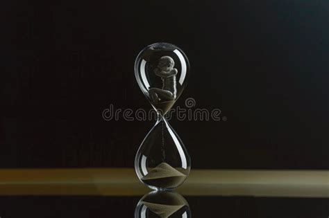 An Hourglass With Sand Trickling Down And A Figure Trapped Within The