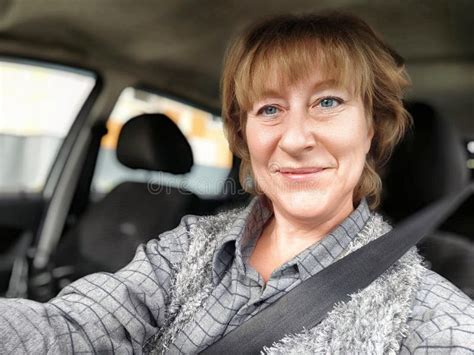 A Middle Aged Woman Smiles While Driving In Her Car On A Sunny
