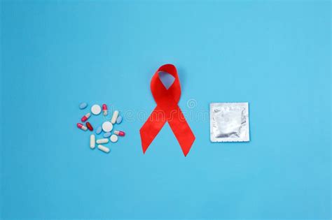Red Ribbon Awareness With Condom And Pills On Blue Background Stock