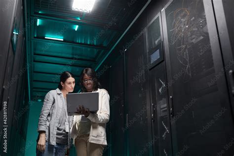 waist up portrait of two female it engineers setting up server network