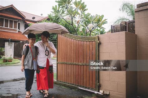 비가 오는 날 학교에서 돌아오는 아시아 계 중국인 소년이 어머니와 함께 집 앞에서 우산을 들고 돌아왔습니다 10 11세에 대한