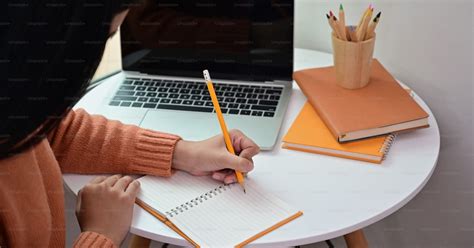 편안한 거실 위의 흰색 작업 책상에 앉아 메모를 하는 매력적인 여성의 자른 이미지 사진 Unsplash의 컴퓨터 이미지