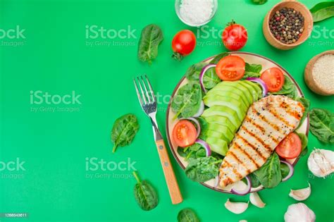 구운 닭 가슴살과 시금치 잎 아보카도 토마토를 녹색 배경에 곁들인 신선한 야채 샐러드 고기와 채소 샐러드 케토겐 다이어트 식이