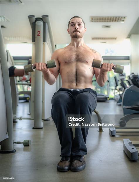Handsome Muscular Man Pumps Up His Muscles Lifting Heavy Dumbbell Stock