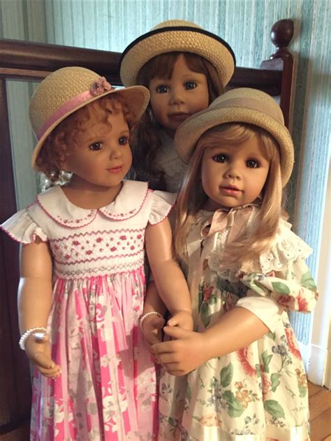 Three Dolls Standing Next To Each Other In Front Of A Wooden Shelf With