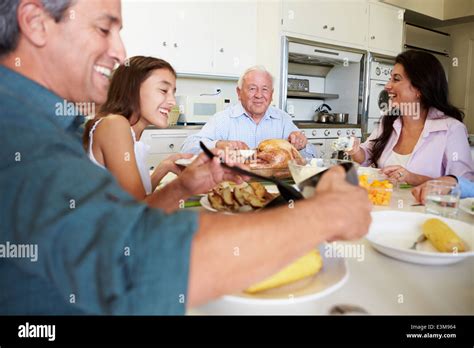 Multi-Generation Family Sitting Around Table Eating Meal Stock Photo - Alamy