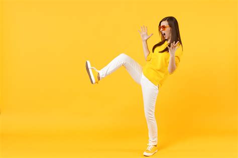 캐주얼 옷 노란 주황색 벽 배경에 고립 된 무언가를 발로 하는 손바닥을 보여주는 심장 안경에서 야생 젊은 여자의 측면도 사람들은 진심으로 감정 라이프 스타일 개념입니다 복사