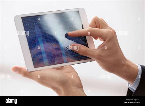 Man Using Tablet Computer With Stock Chart Data On Screen Against Light Background Forex