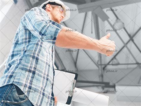 عکس مهندس ساختمان با کلاه ایمنی و نقشه در دست عکس با کیفیت و تصاویر