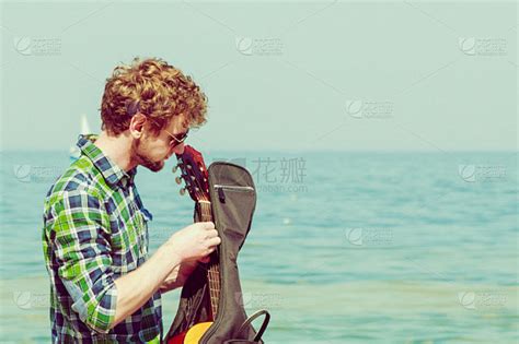 留着胡子的年轻潮男在户外拿着吉他