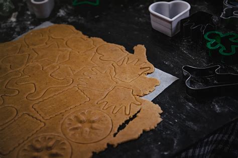 어두운 배경에 양피지 베이킹 종이에 원시 반죽에서 크리스마스 트리 스타 작은 남자 마음의 형태로 진저 브레드 쿠키를 잘라 맨 위 보기 공간 절약 0명에 대한 스톡 사진 및