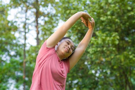 Young Asian Woman In Sportswear Stretches Before Exercising In The Park