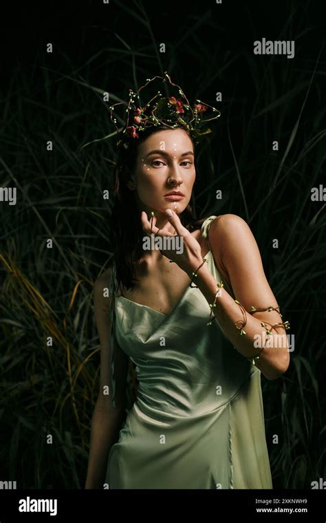 Woman In Green Dress Gracefully Poses In Forest With Floral Crown Stock