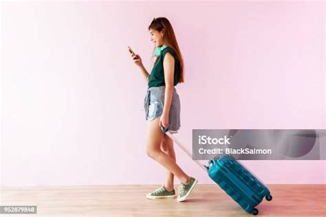 행복 한 젊은 여행자 여자 산책 가방 및 음악 헤드폰 스마트폰 보고 얼굴 및 미소 배경 전체 길이 측면 모습으로 다채로운 파스텔 벽 여자에 대한 스톡 사진 및 기타 이미지