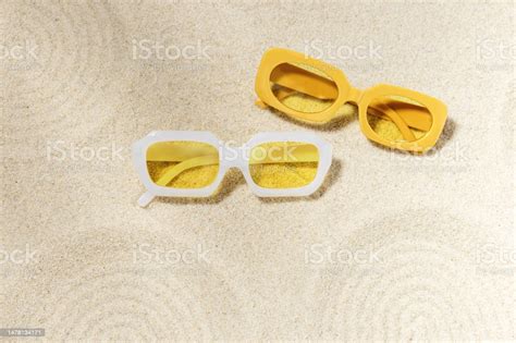 햇빛에 모래 배경에 세련된 흰색과 노란색 선글라스 컬러 유리가 있는 여름 패션 컬렉션 안경 여름 세일 개념입니다 상위 뷰 라이프
