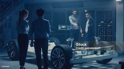 전기 자동차 섀시 플랫폼에서 일하는 자동차 엔지니어 팀 조치를 취하고 3d Cad 소프트웨어로 작업하고 효율성을 분석합니다 바퀴 엔진 및 배터리와 차량 프레임 상승 된 샷