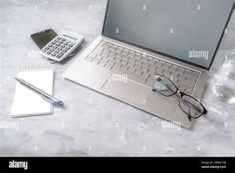 Workplace With Laptop Calculator And Glasses On A Gray Office Desk