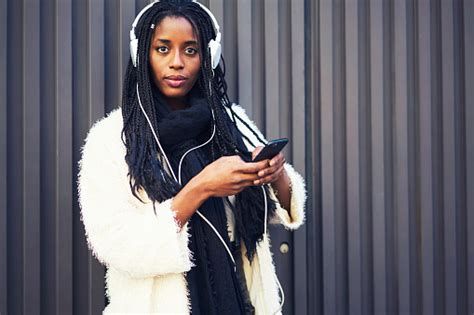 스마트폰 및 헤드폰을 통해 매력적인 Hipster 여자 라디오 방송 듣고 재생 목록에서 좋아하는 작곡을 즐기는 심각한 아프리카 미국 여성 음악 애호가의 반 길이 초상화