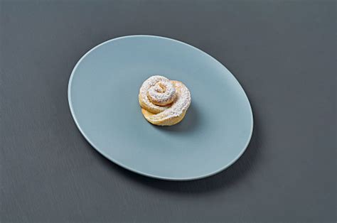 회색 둥근 접시에 가루 설탕의 장미 스팽글 형태로 만든 구운 빵 하나는 어두운 콘크리트 책상에 놓여있다 제과 작업장 클로즈업 가루 설탕에 대한 스톡 사진 및 기타 이미지