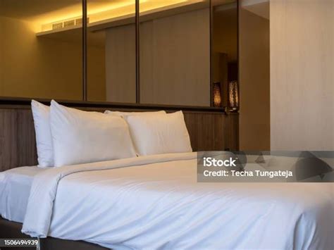 호텔 침실에 큰 거울 벽 배경이 있는 고급스러운 현대적인 디자인 인테리어에 흰색 이불이 있는 빈 침대에 흰색 베개를 커플링합니다 손님을 위해 준비하는 부드럽고 깨끗한 편안한