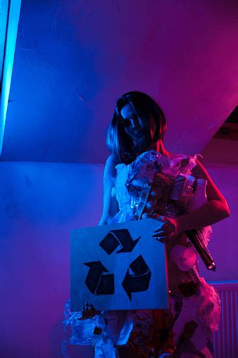 리사이클 사인 플라스틱과 골판지로 만든 쓰레기 드레스를 입고 웃는 여성 에코 파이터의 초상화는 오염 인식 개념에서 환경 청소 자연을 확산하는 데 도움이 생생한 미친 네온