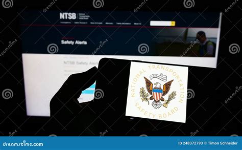 Person Holding Cellphone With Seal Of US National Transportation Safety Board NTSB On Screen