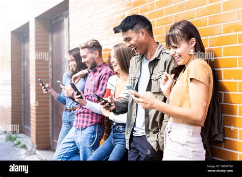 Multicultural Friends Laughing Using Smartphone At Wall On University