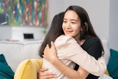 아름다운 한국인 아시아 친구들은 소파에 있는 거실에서 오랜 만에 만나 인사를 나누고 서로를 껴안고 감정과 감정 갈망을 표현하며