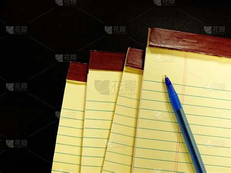 桌上有几本蓝色钢笔的笔记本，用于商务工作、家庭作业或个人项目