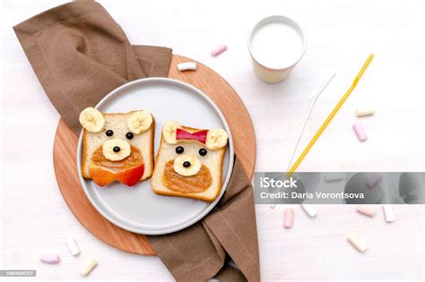 재미 있고 귀여운 곰 개는 땅콩 버터 바나나 사과 우유 마시멜로를 곁들인 샌드위치 토스트 빵을 직면합니다 어린이 어린이 아기의