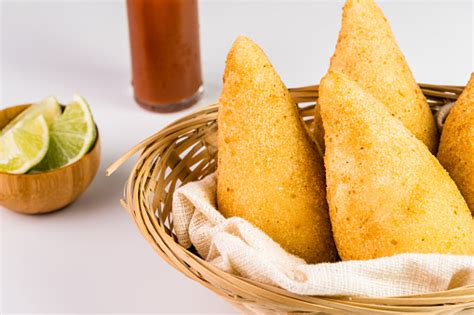 브라질의 Coxinha로 알려진 전통 간식 인 치킨 콕 시냐 옆에 레몬과 후추와 같은 향신료와 함께 바구니에 담겨 제공됩니다